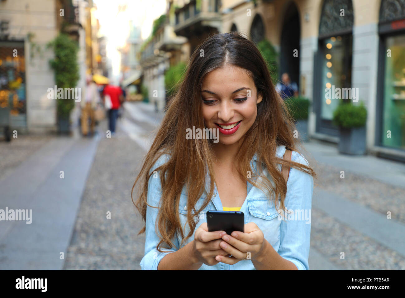 Beautiful young woman messaging on the smart phone with Milan city ...
