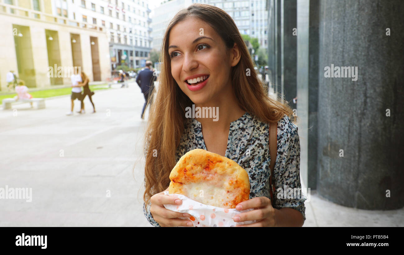 Happy young business woman eating a small pizza in her short lunch ...