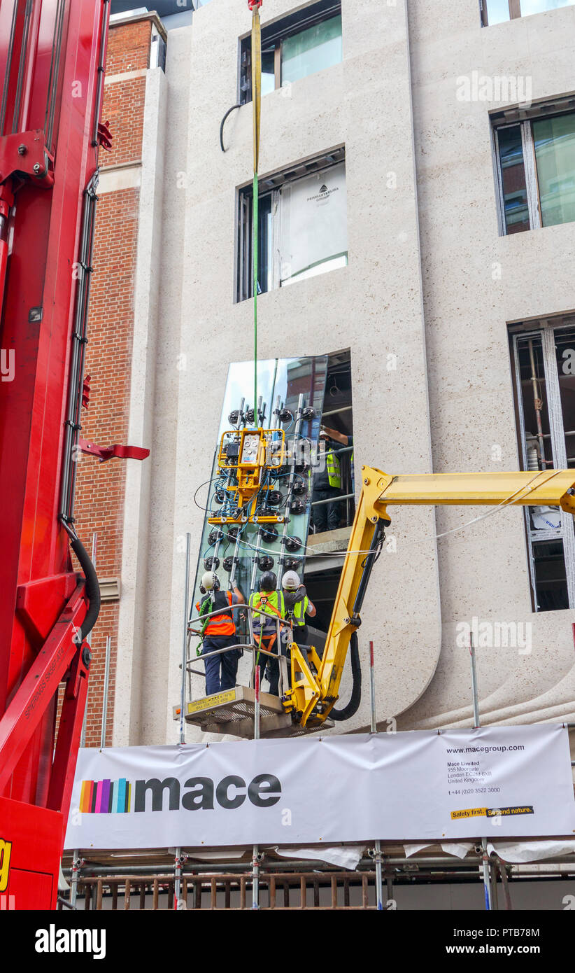 Building contractor Mace workers on a cherry picker hoist carefully ...