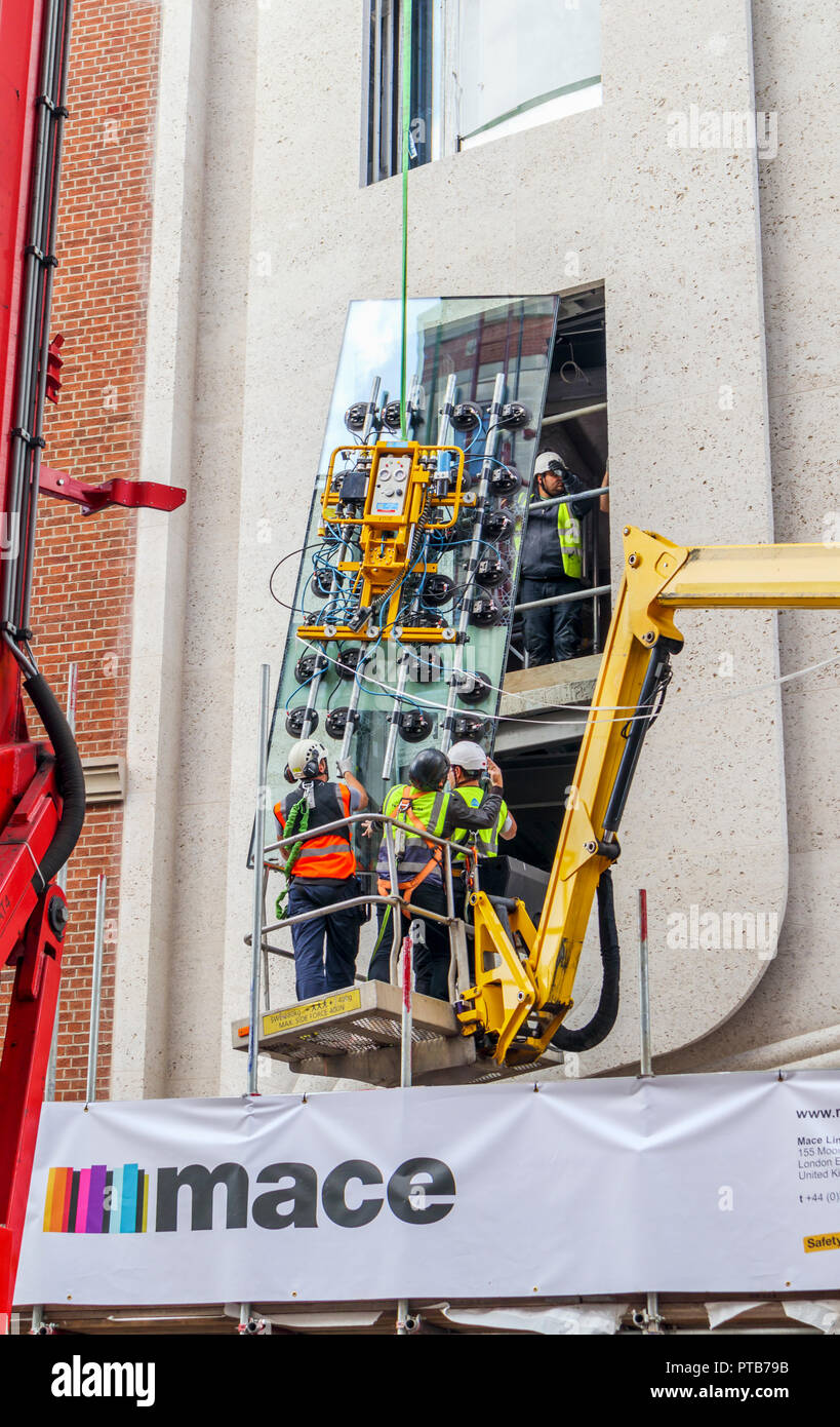 Building contractor Mace workers on a cherry picker hoist carefully ...