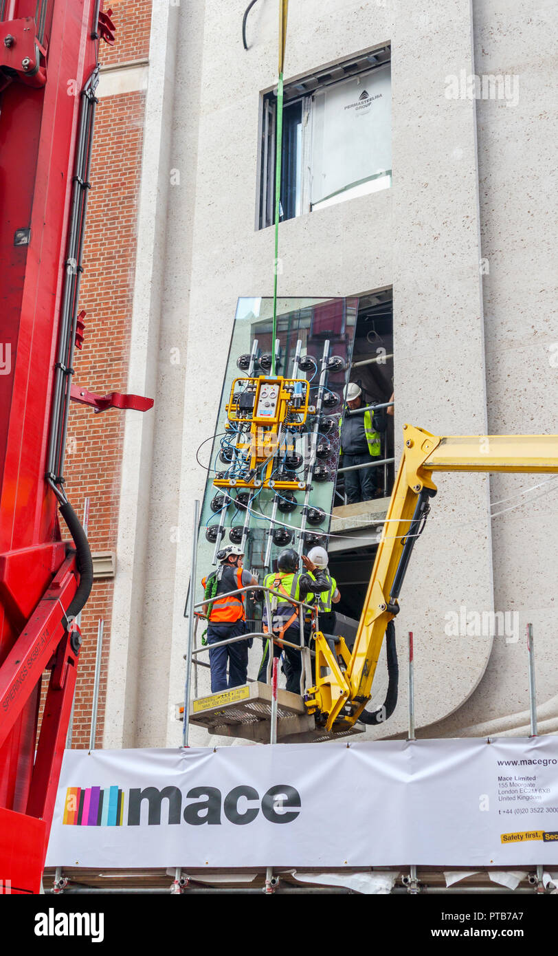 Building contractor Mace workers on a cherry picker hoist carefully ...