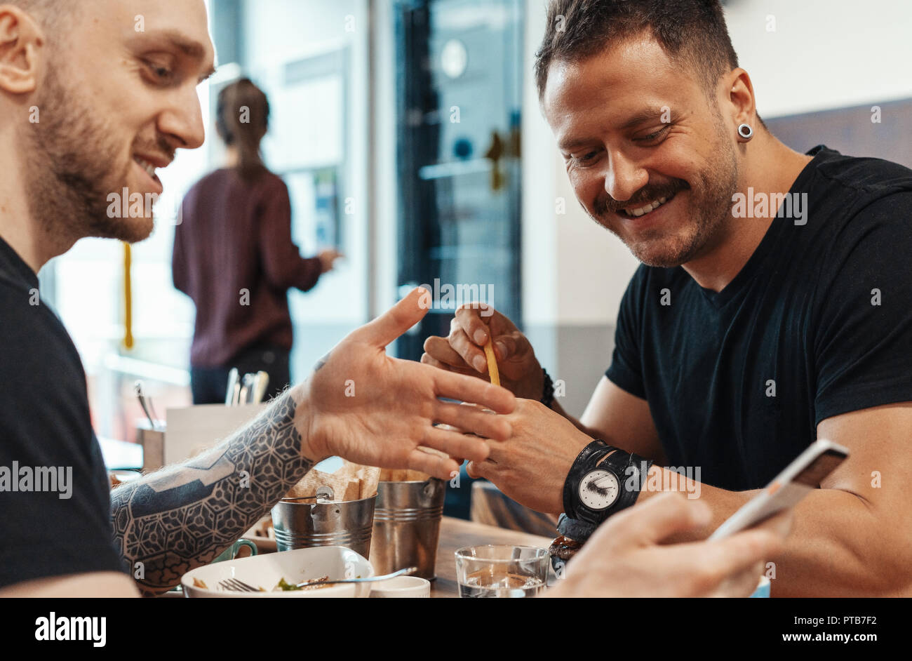 Two friends eating burgers. french fries, having fun and smiling at ...
