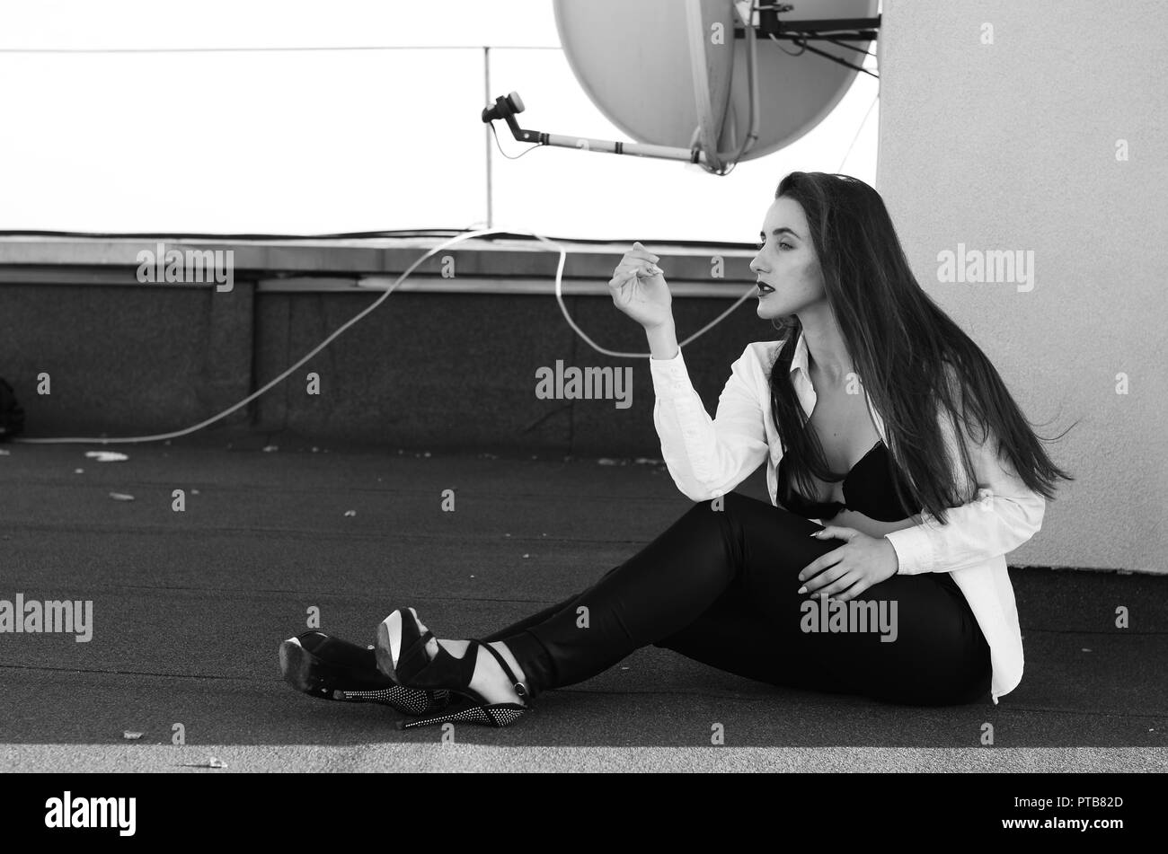A brunette on the roof of a building poses for the camera Stock Photo ...