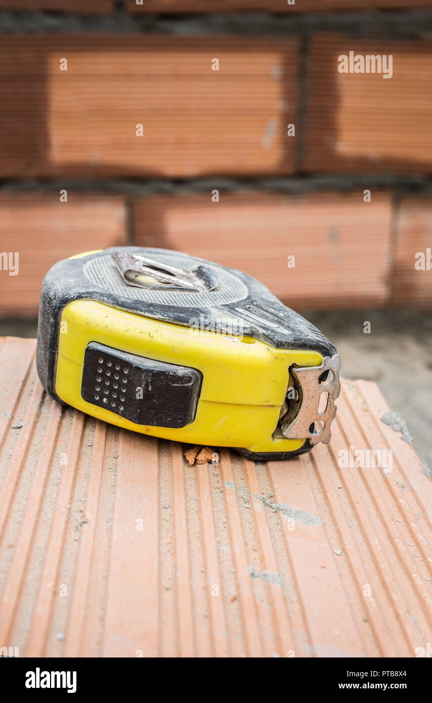 Measuring tape over clay-based bricks. Closeup Stock Photo - Alamy