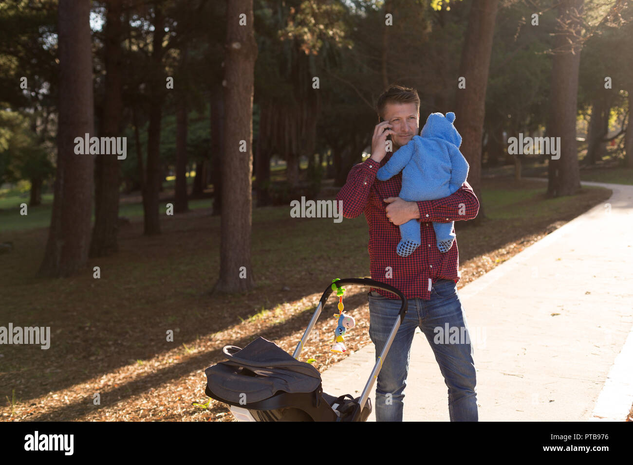 Father talking on mobile phone while holding his baby boy Stock Photo ...