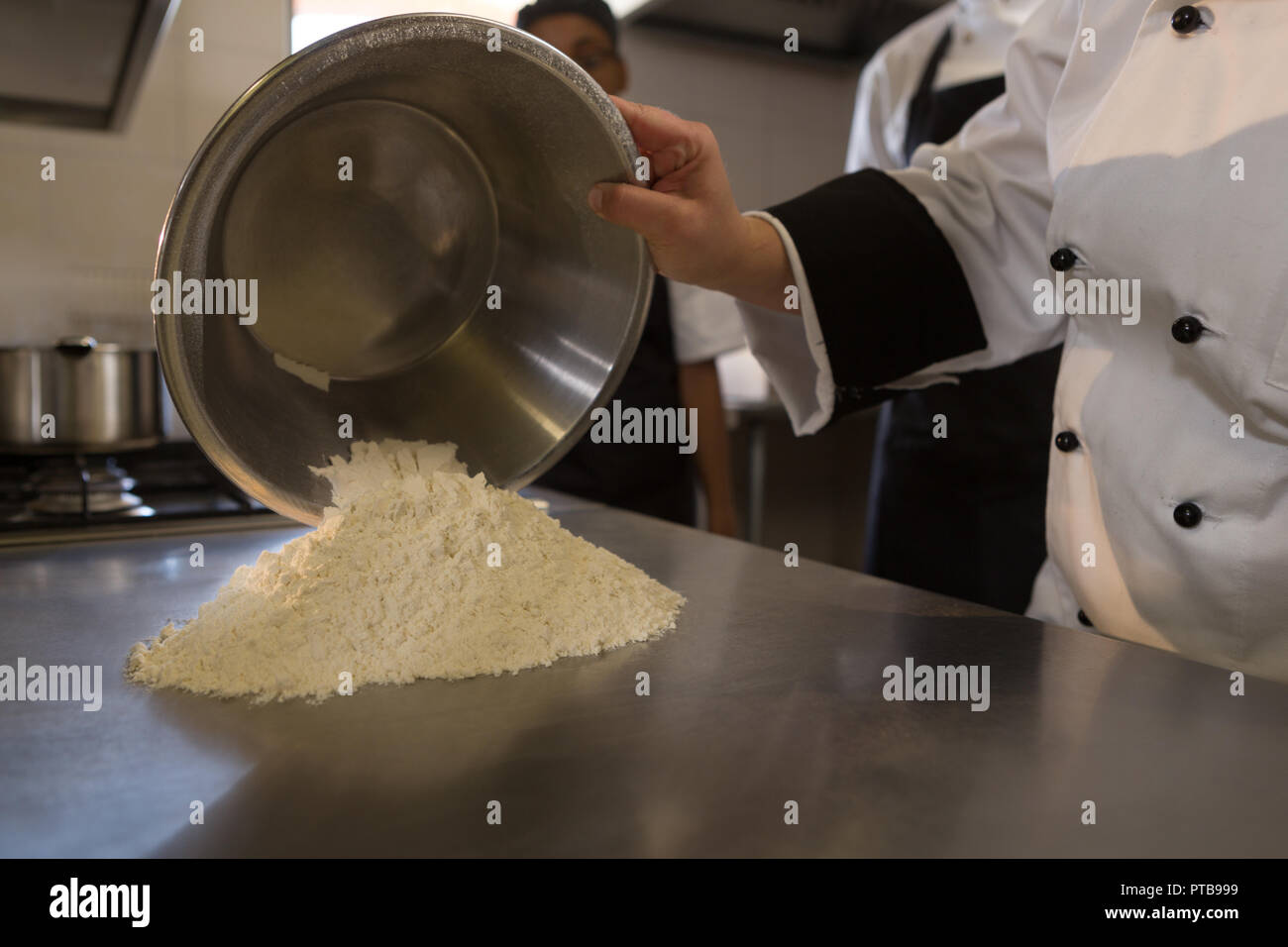 Female chef pouring flour on worktop in kitchen Stock Photo - Alamy