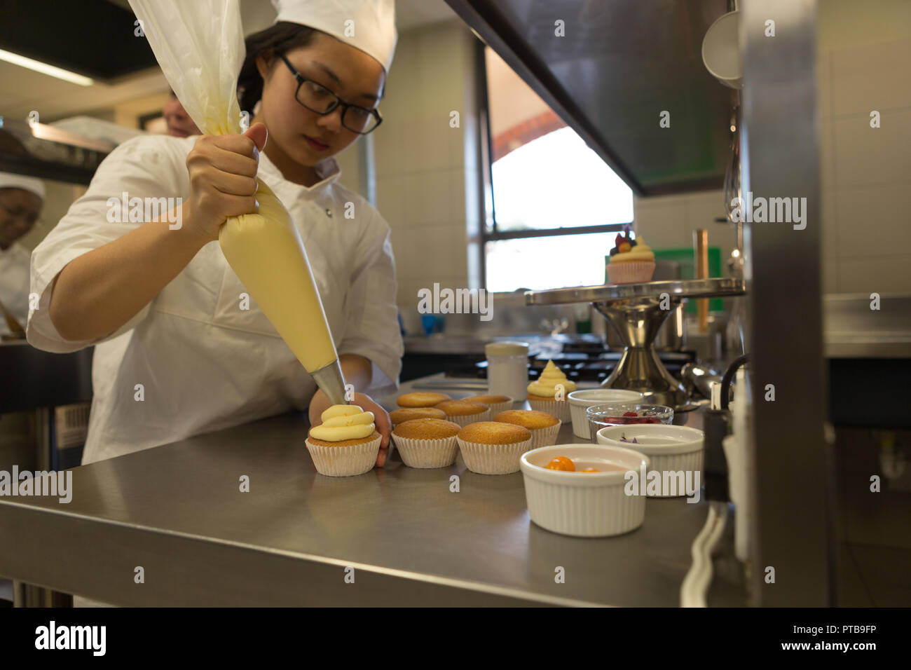 Female chef icing muffins with pastry bag in kitchen Stock Photo - Alamy