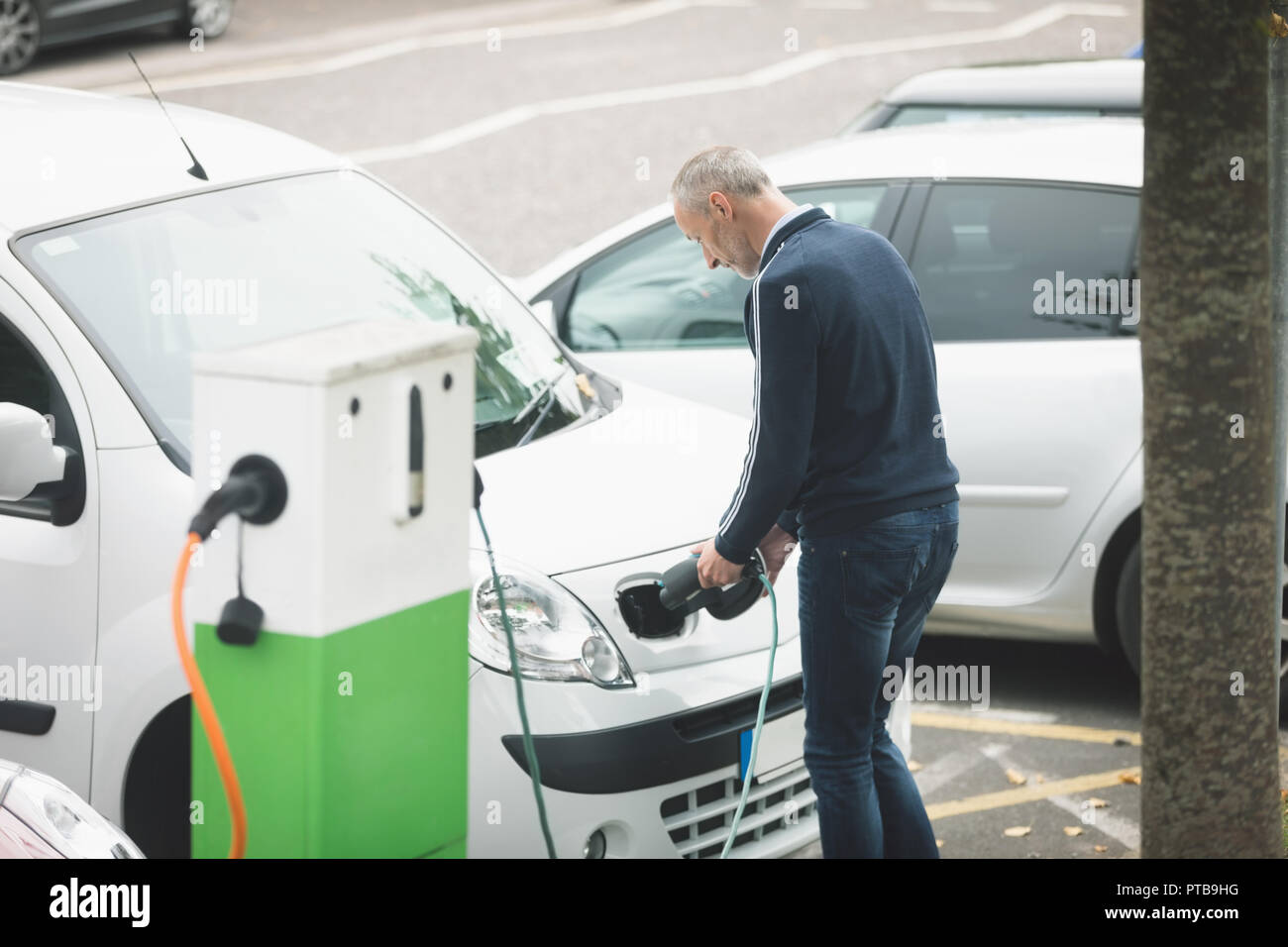 Man charging electric car at charging station Stock Photo - Alamy