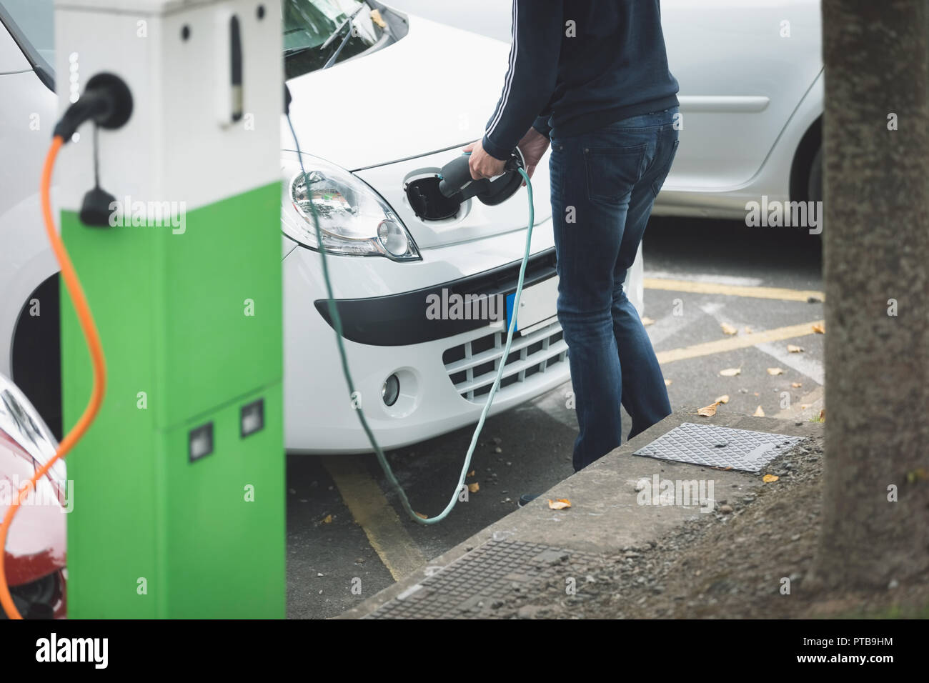 Man charging electric car at charging station Stock Photo - Alamy