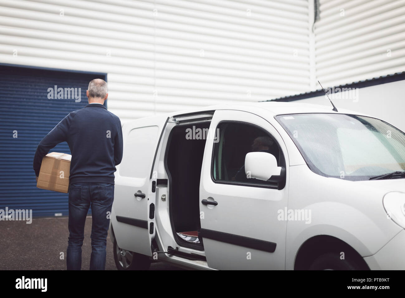 Delivery man carrying parcel at warehouse Stock Photo - Alamy