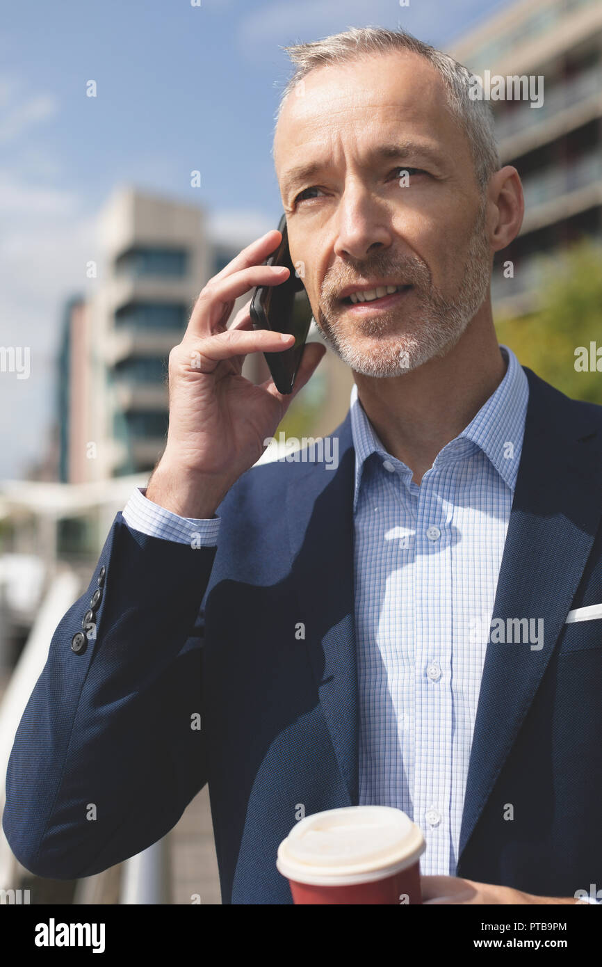 Businessman talking on mobile phone in city Stock Photo - Alamy