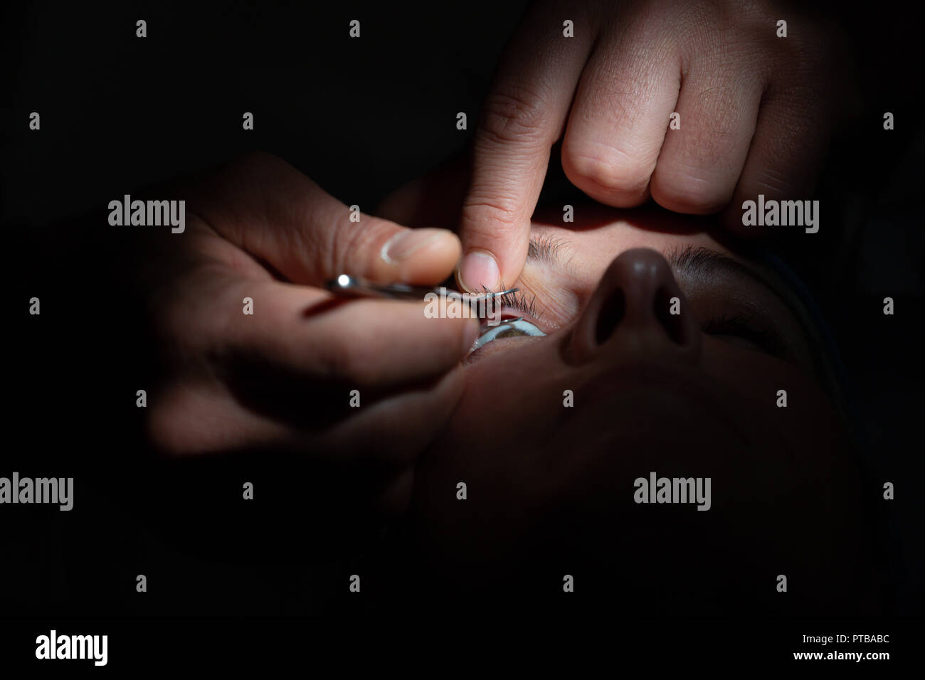 Optometrist examining patient eyes with eye test equipment in clinic ...