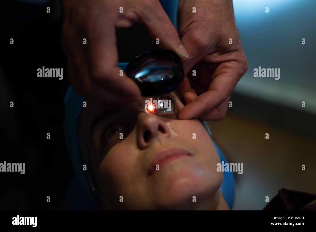 Optometrist examining patient eyes with eye test equipment in clinic ...