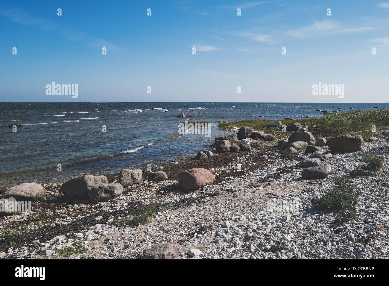 rocky sea beach with wide angle perspective over the sea with sunny sky ...