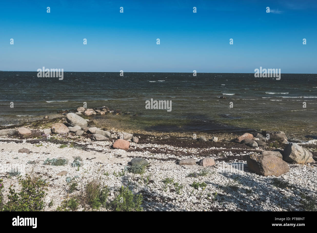 rocky sea beach with wide angle perspective over the sea with sunny sky ...