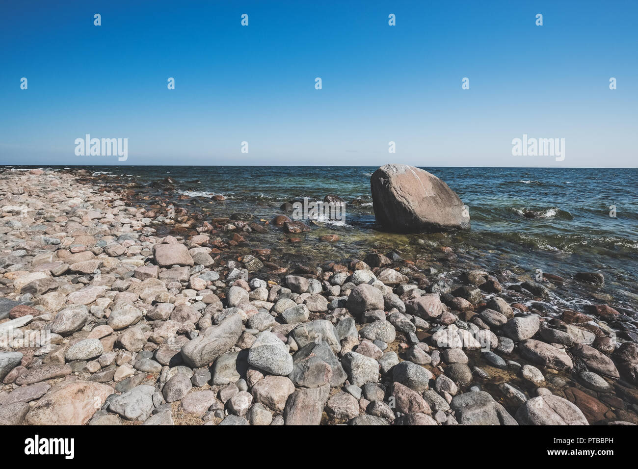 rocky sea beach with wide angle perspective over the sea with sunny sky ...