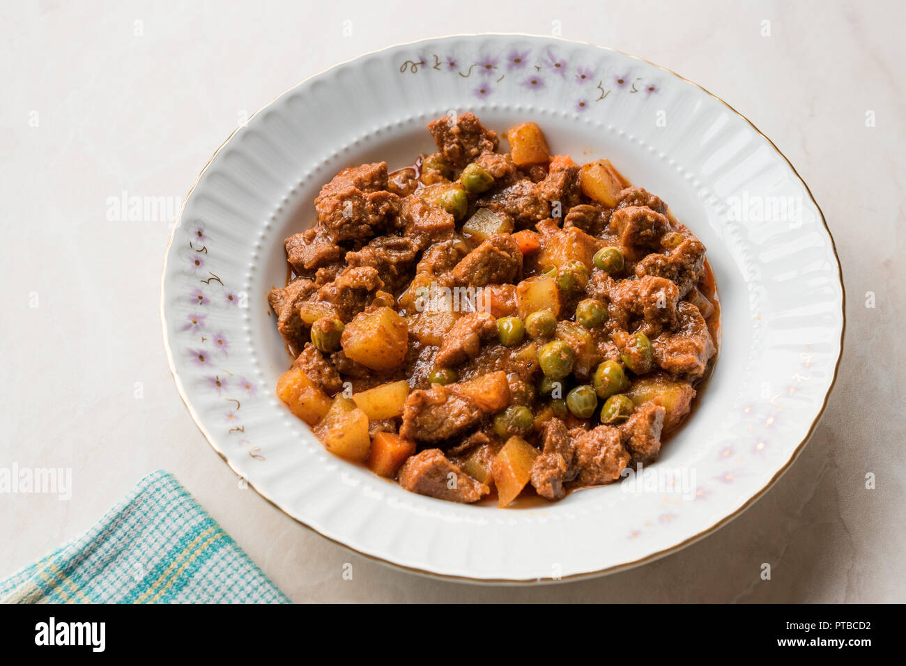 Turkish traditional tas kebab with potato, pea and tomato in a white ...