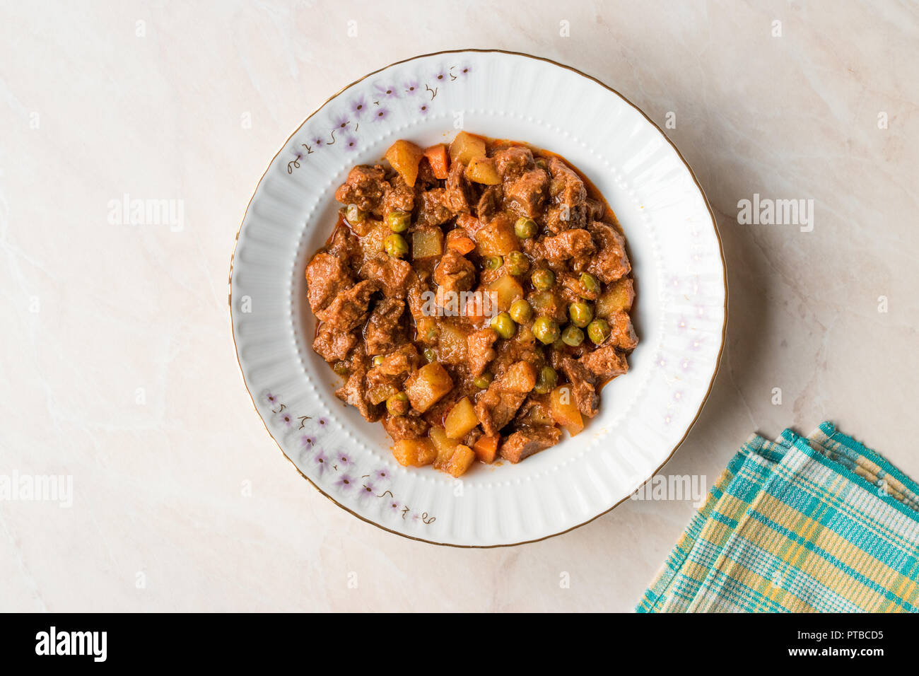 Turkish traditional tas kebab with potato, pea and tomato in a white ...