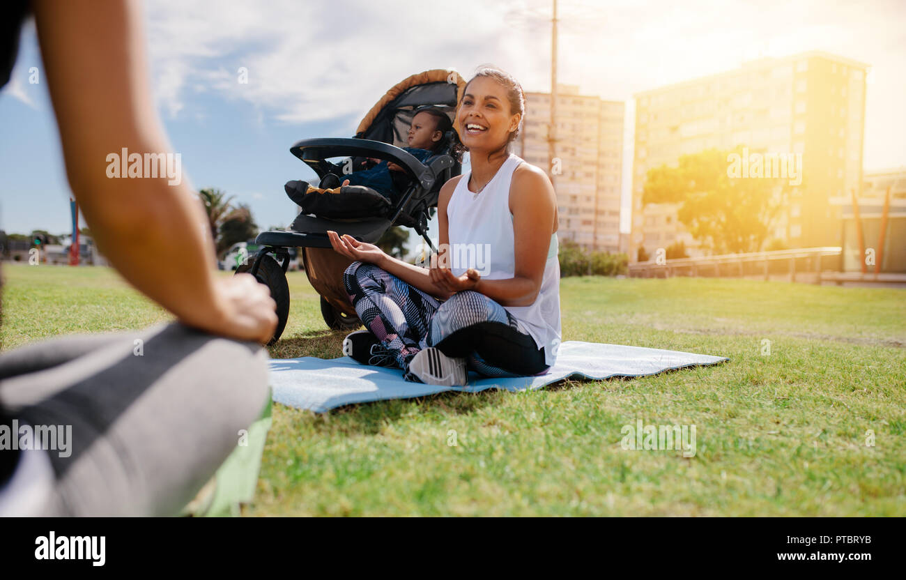 Active mothers doing yoga in park with baby in a stroller. Woman ...
