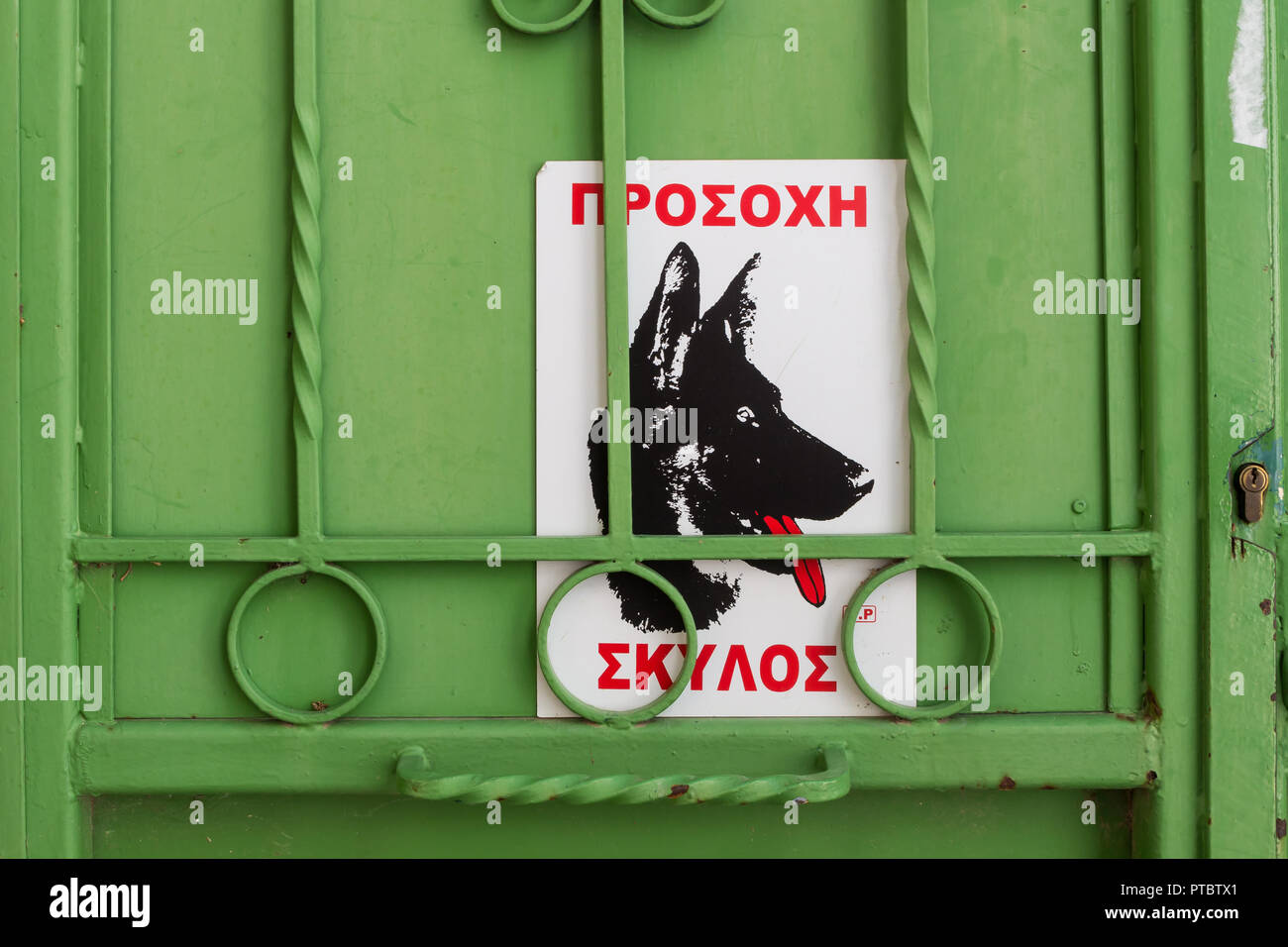 Green gate with a lock and a sign with a warning of a dog in greek ...