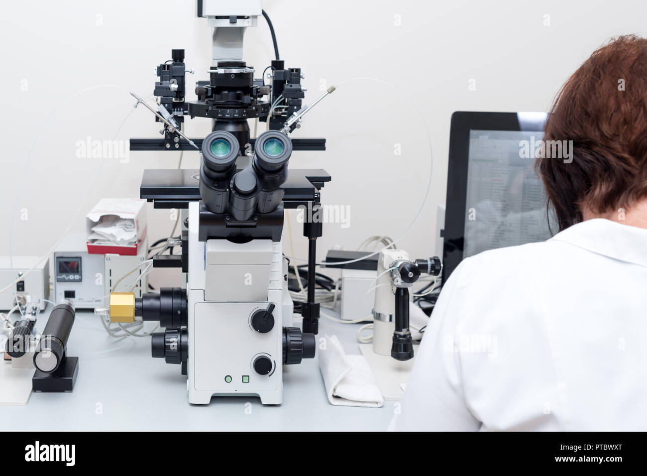 Doctor or scientist working with computer and microscope in biotech lab ...