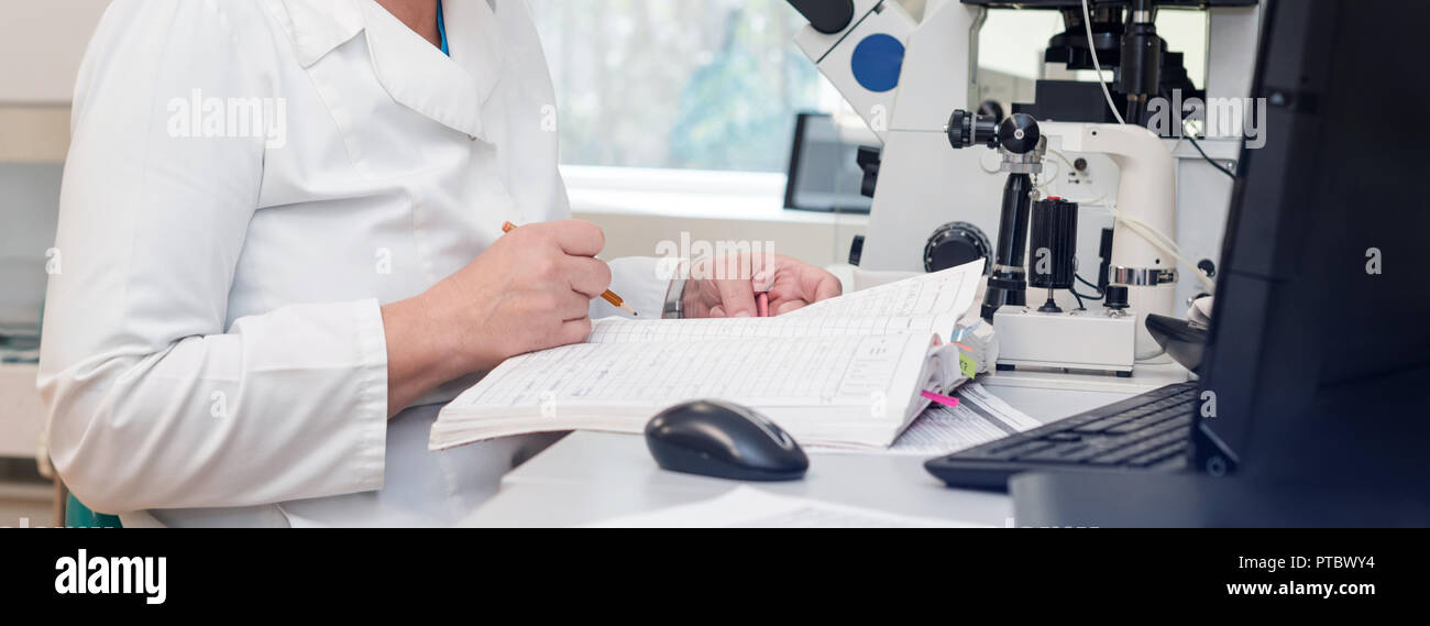 Doctor or scientist working with computer and microscope in biotech lab ...