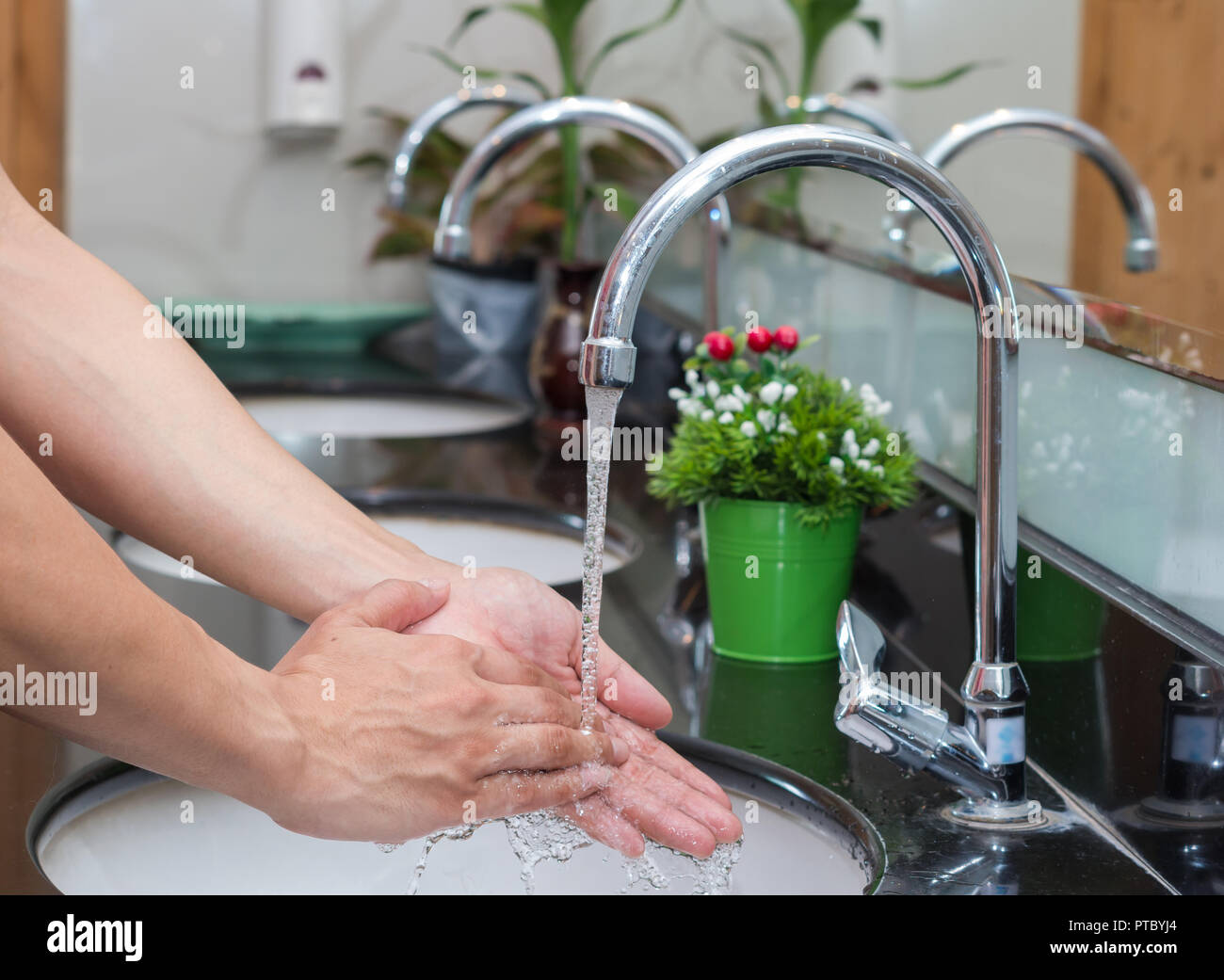 Hand washing with Chrome faucet over the washbasin in modern bathroom ...
