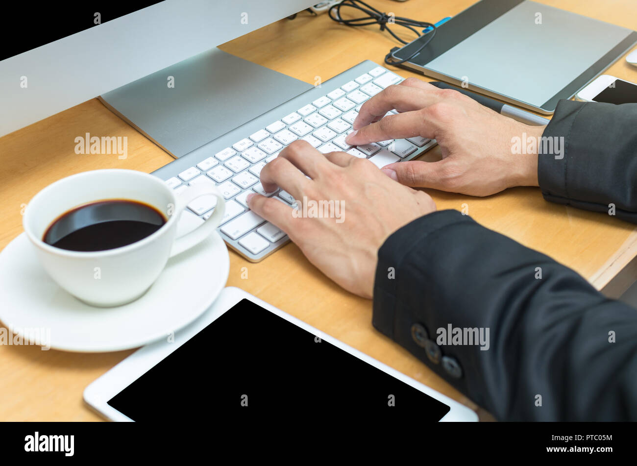 Rear view of a businessman working with a computer and tablet at office ...