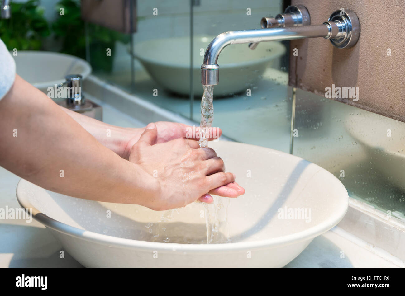 Hand washing with Chrome faucet over the washbasin in modern bathroom ...