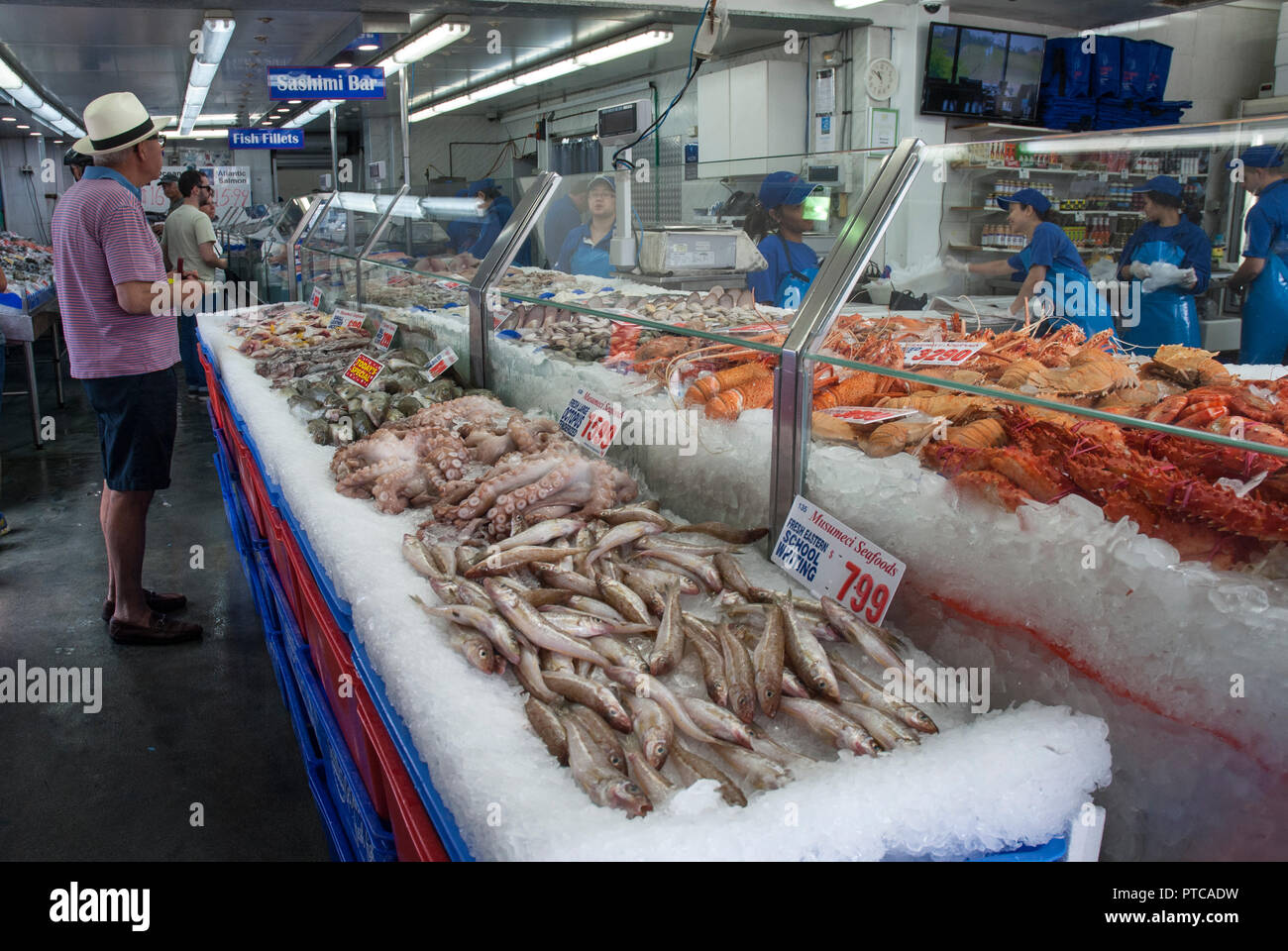 Inside the Sydney Fish market with well lit stalls and counters covered ...
