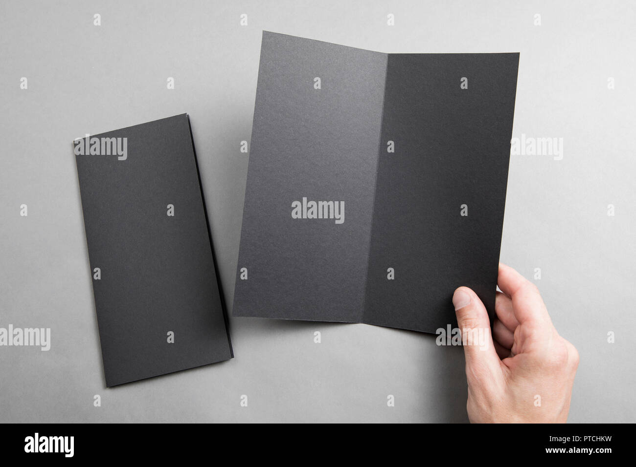 Mens hand holding empty black booklet on gray background. View from ...