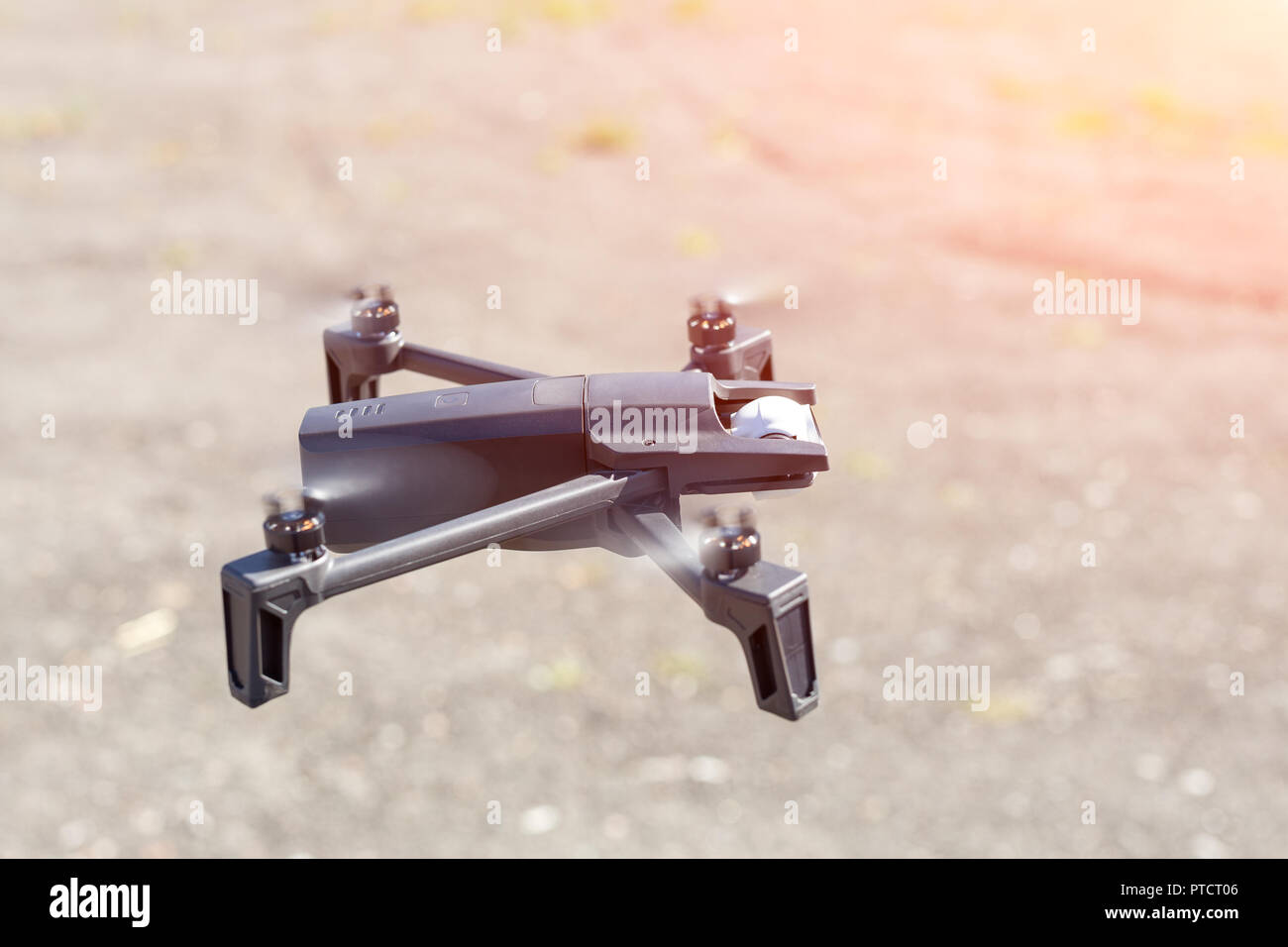 Back view of Small compact drone flying against sun and clear sky on ...