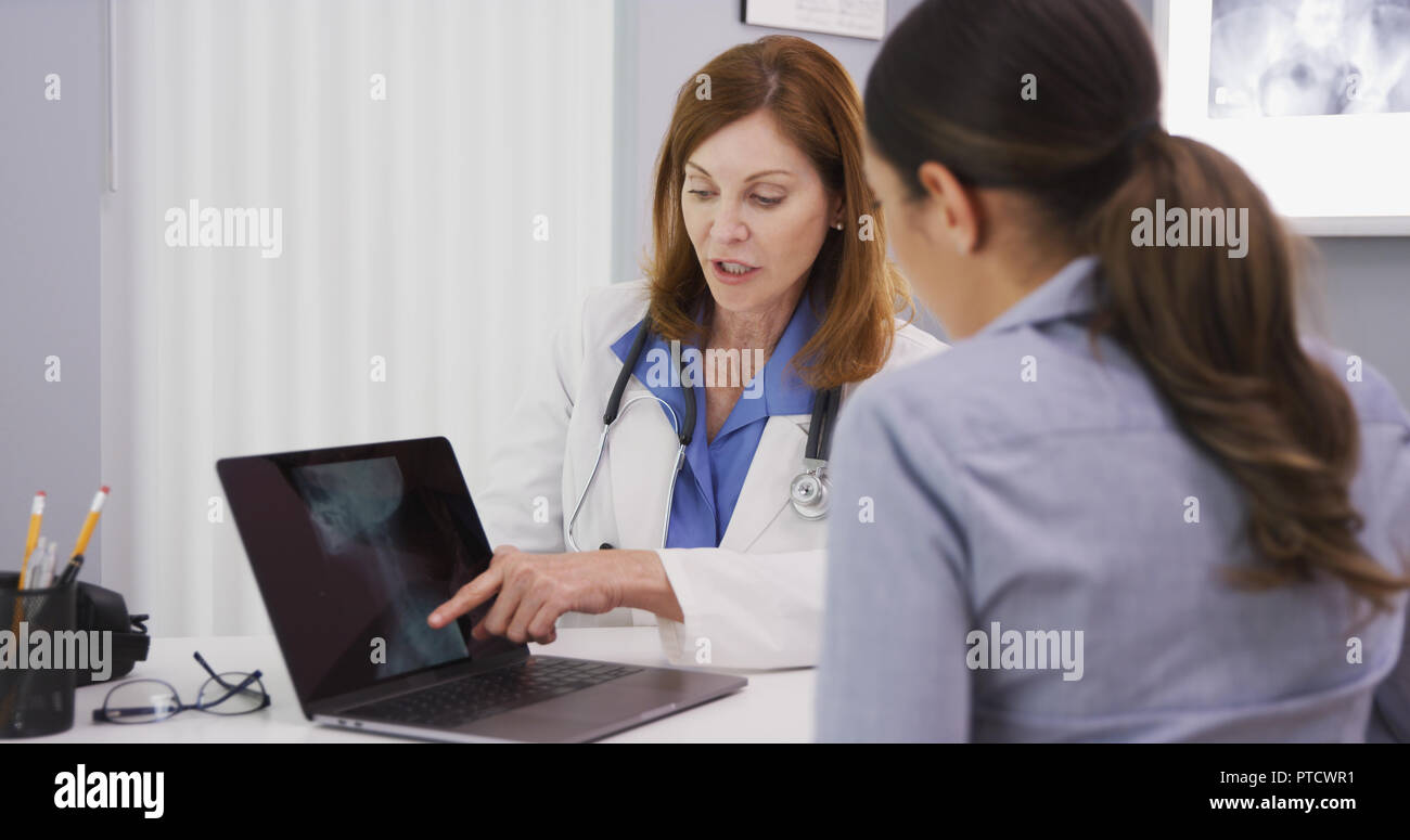 Senior doctor showing xray of spine neck and cranium to young female ...