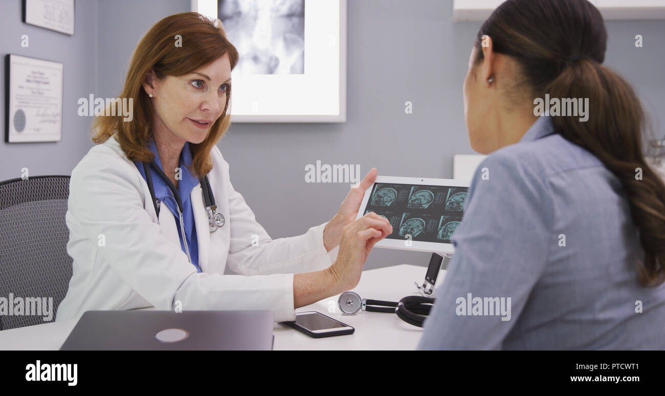 Young latina patient reviewing ct scan of cranium with middle aged ...
