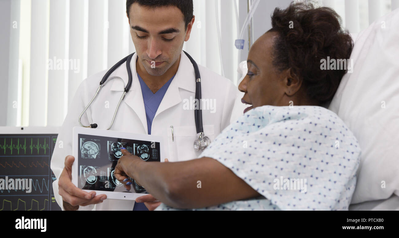 Portrait of hispanic medical doctor showing ct-scans on tablet to ...