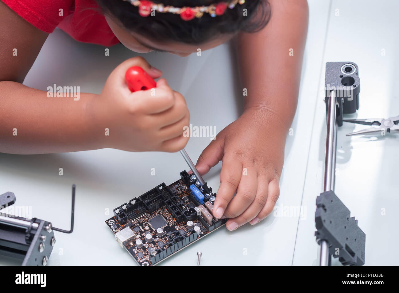 Little hands of a smart kid working on electronic device with a screw ...