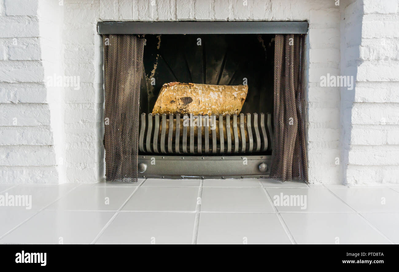 Unlit Fire place with white architecture and non burning logs inside ...