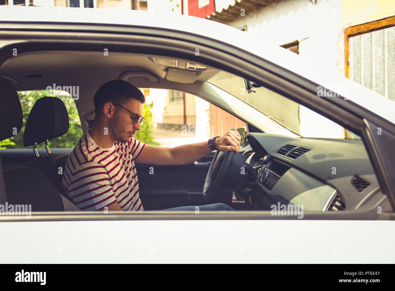 Man in his car in some neighborhood looking down Stock Photo - Alamy