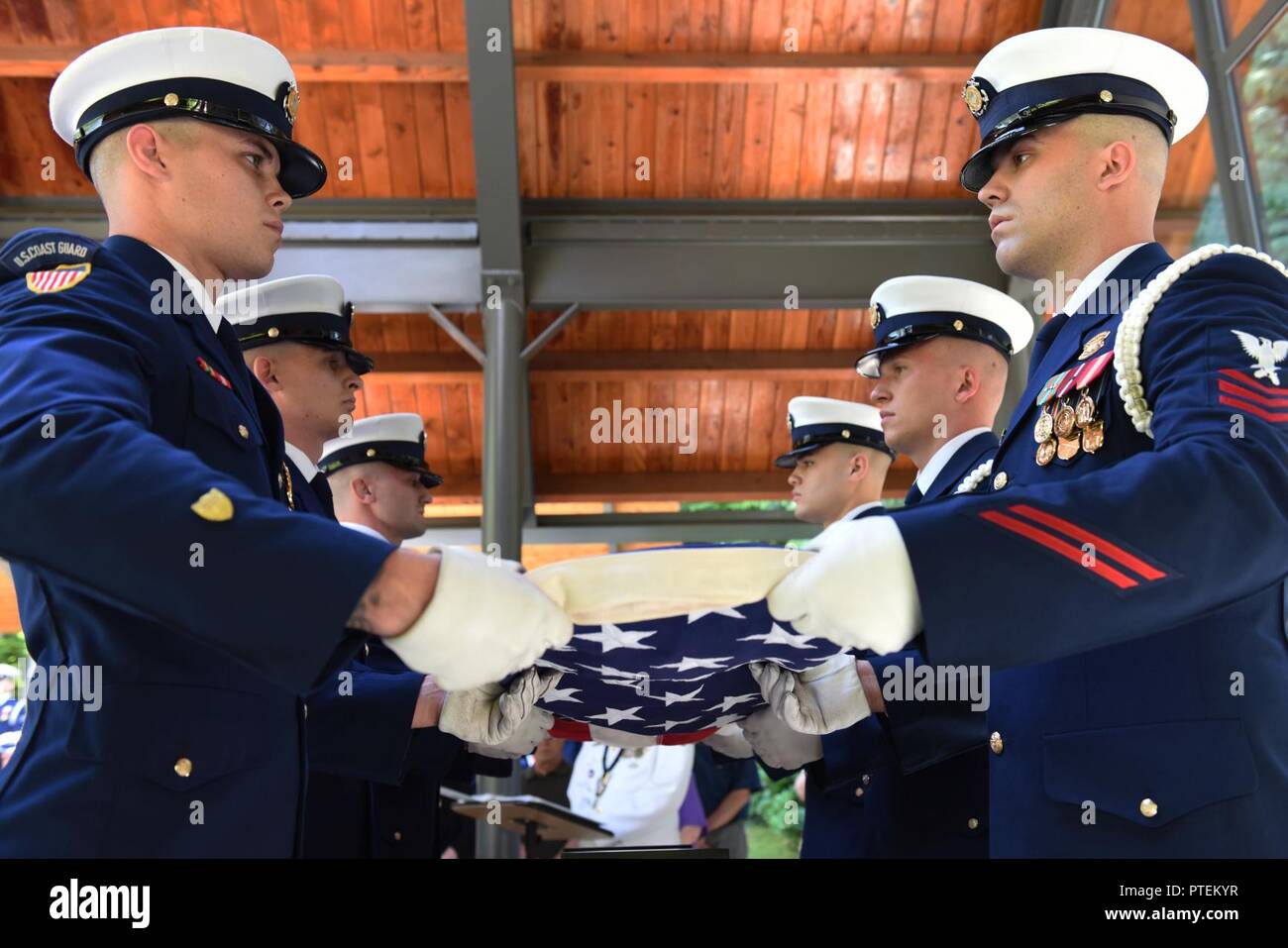 Coast Guard members fold an American flag during a funeral ceremony ...