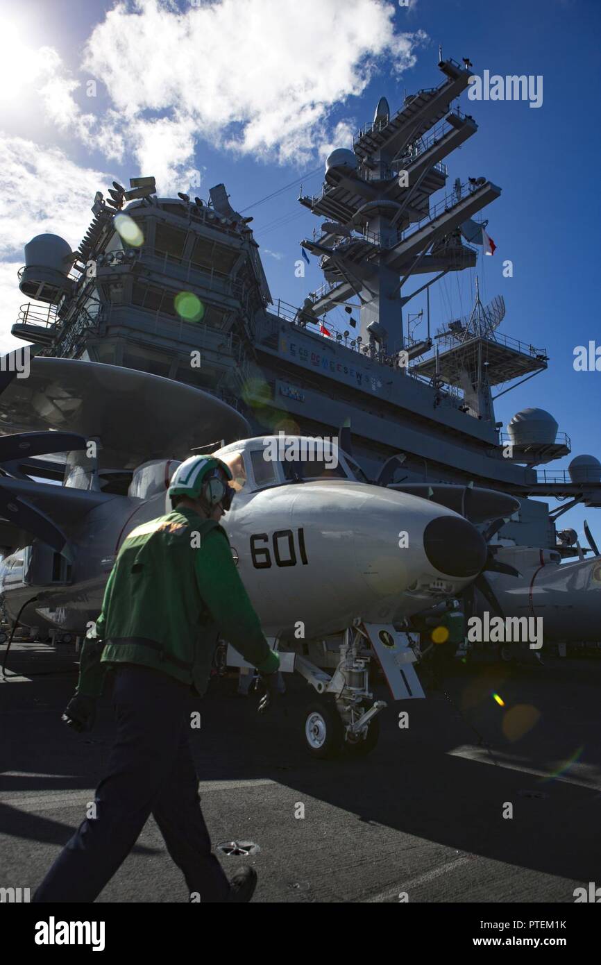 A United States Navy sailor walks past an E-2 Hawkeye airborne early ...