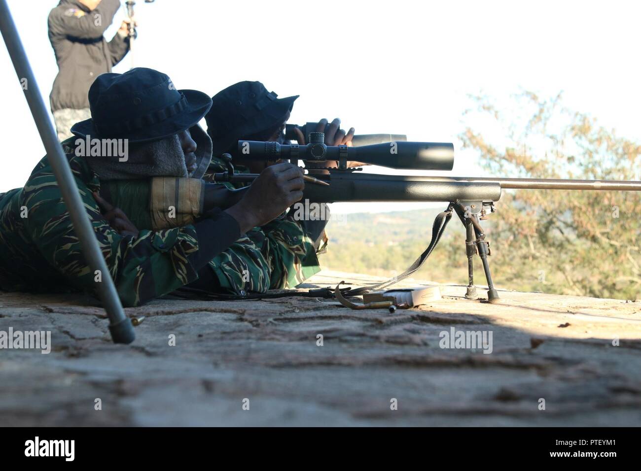 A Guyanese sniper loads a round into his rifle while his teammate scans ...