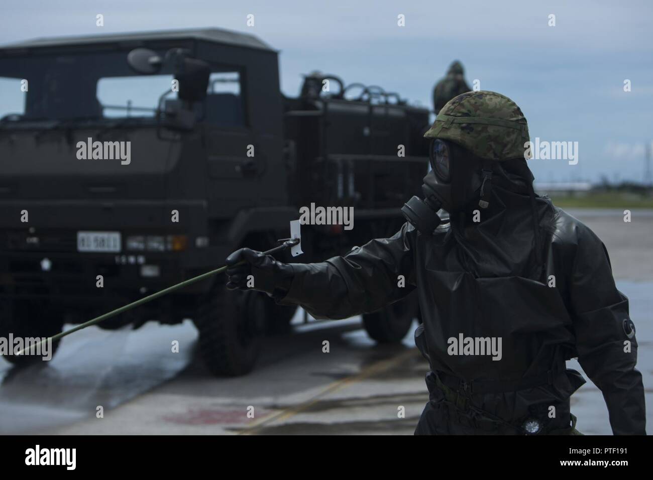 A Japanese Ground Self-Defense service member directs a decontamination ...