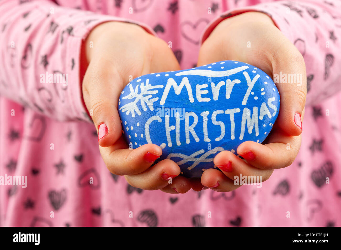 Young child hands holding blue painted rock with Merry Christmas hand ...