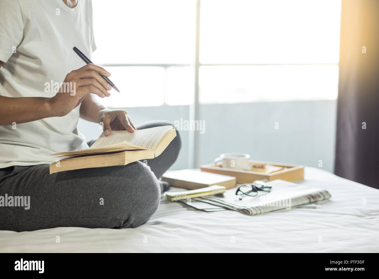 Young woman sitting working and writing in the notebook on bed leisure ...