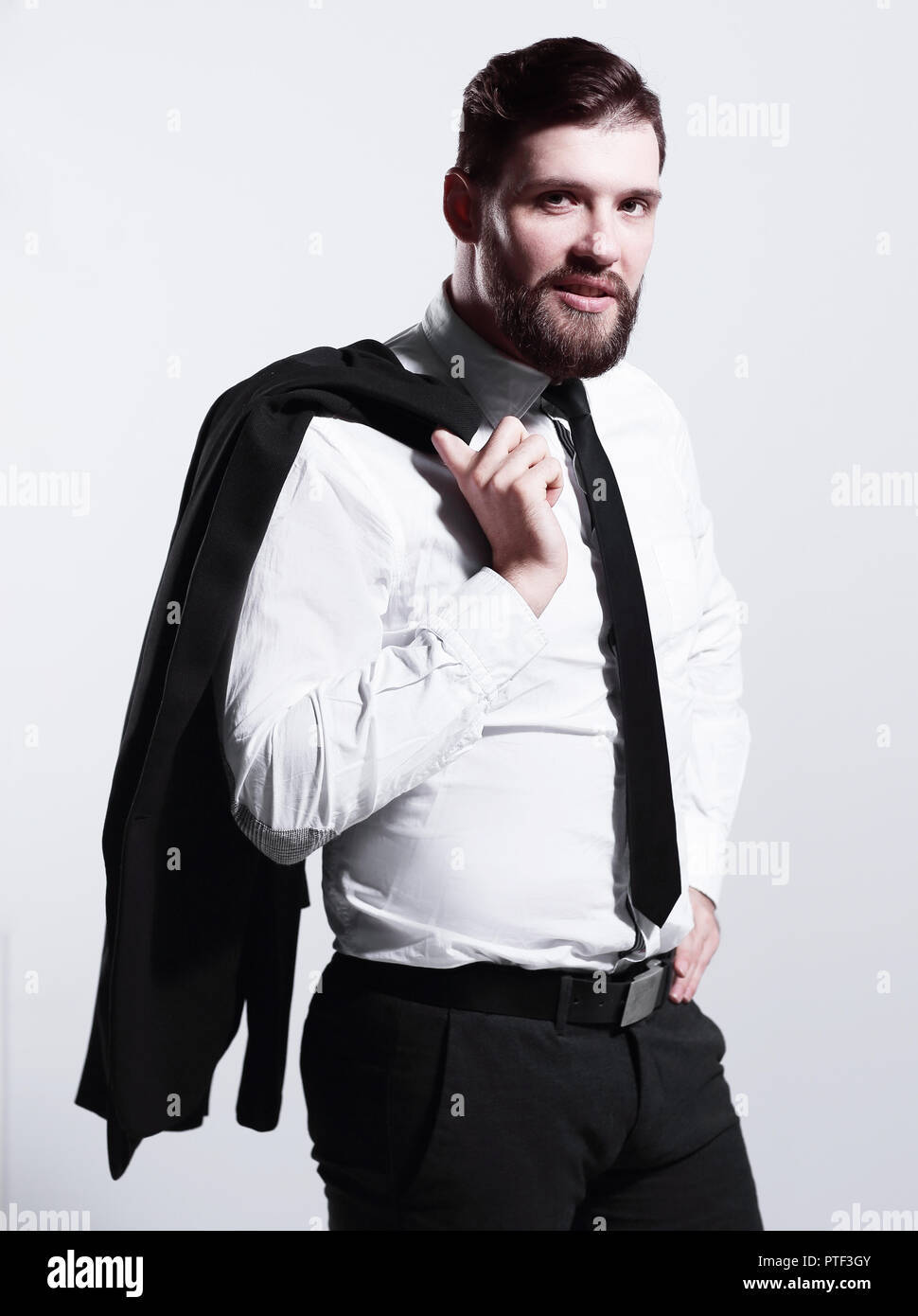 smiling businessman holding a jacket over his shoulder and straightens ...