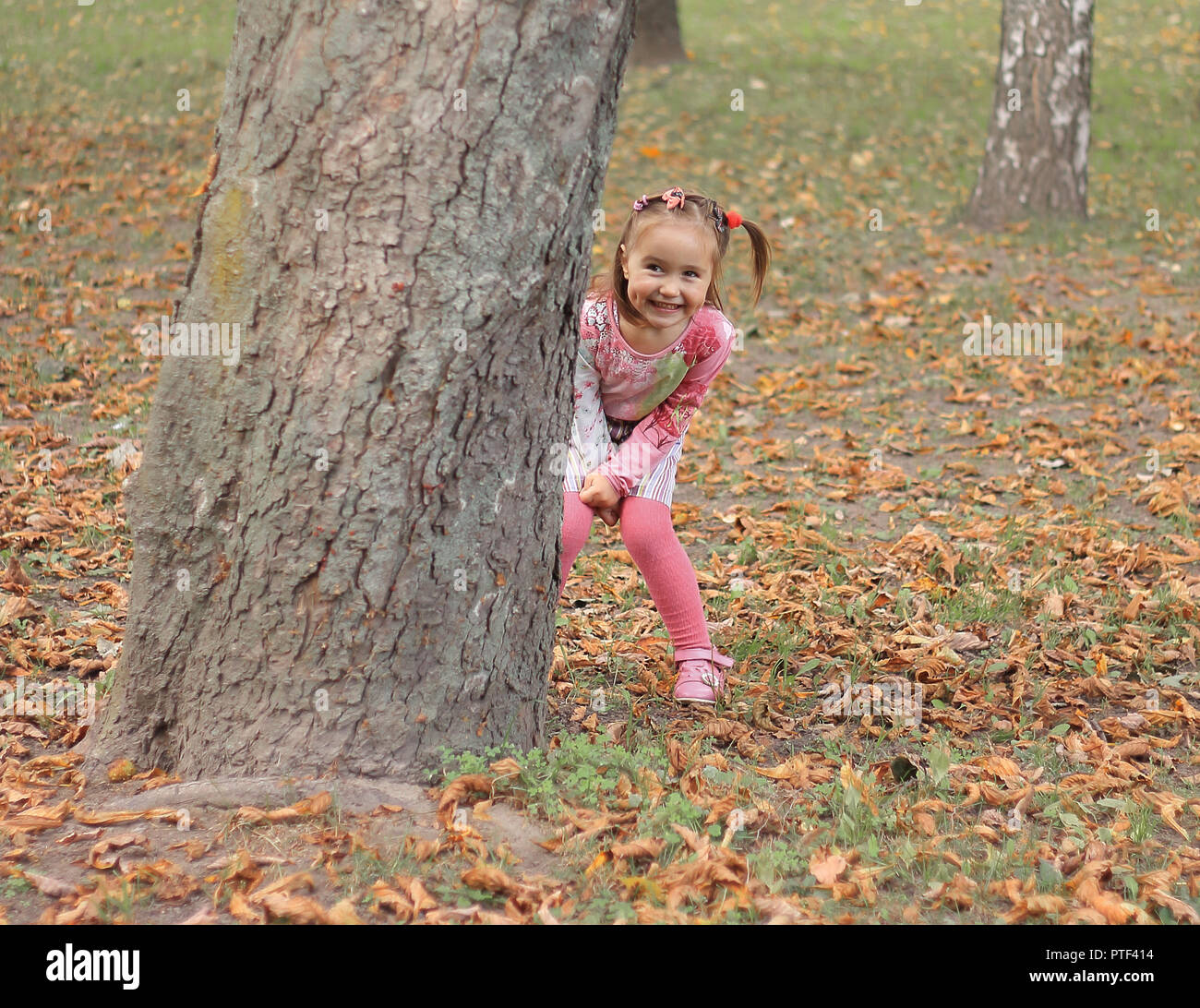 happy little girl playing hide and seek in the city Park Stock Photo ...