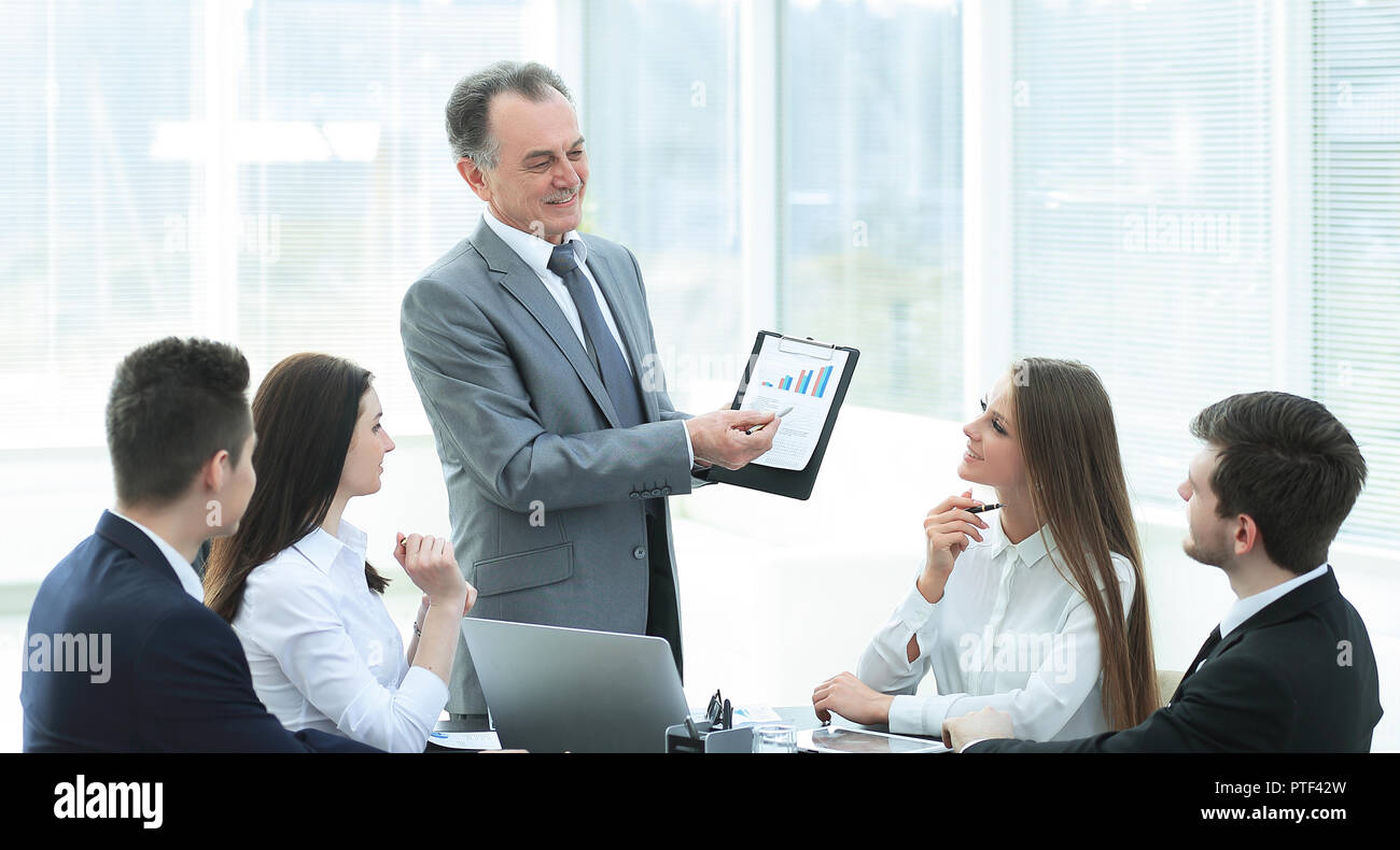 smiling Manager showing a business team ,a graph with financial data ...