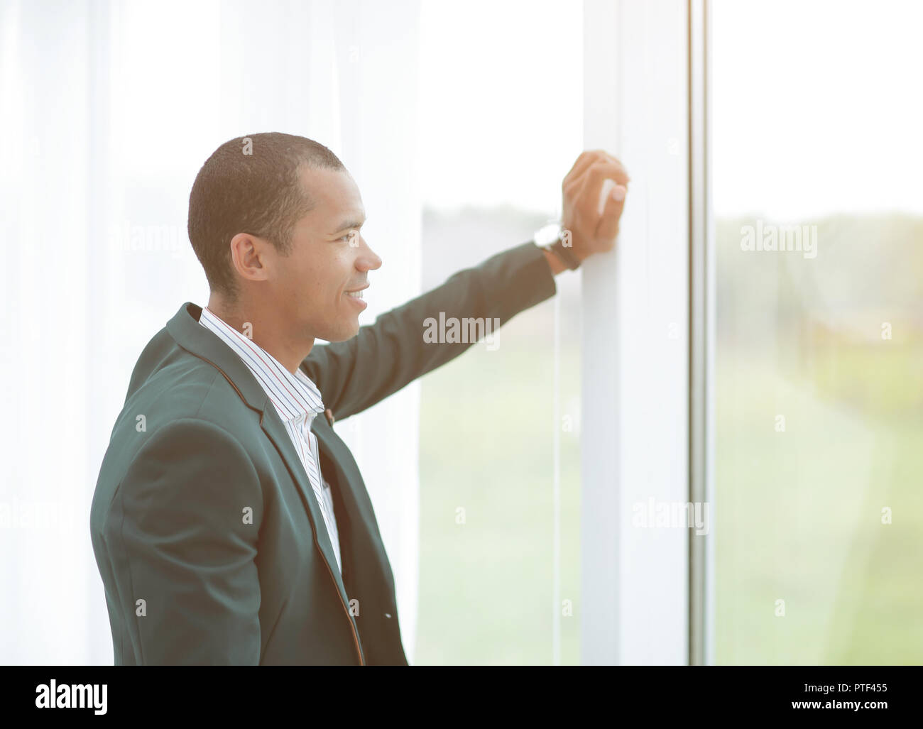 successful young businessman looking at blank office window Stock Photo ...