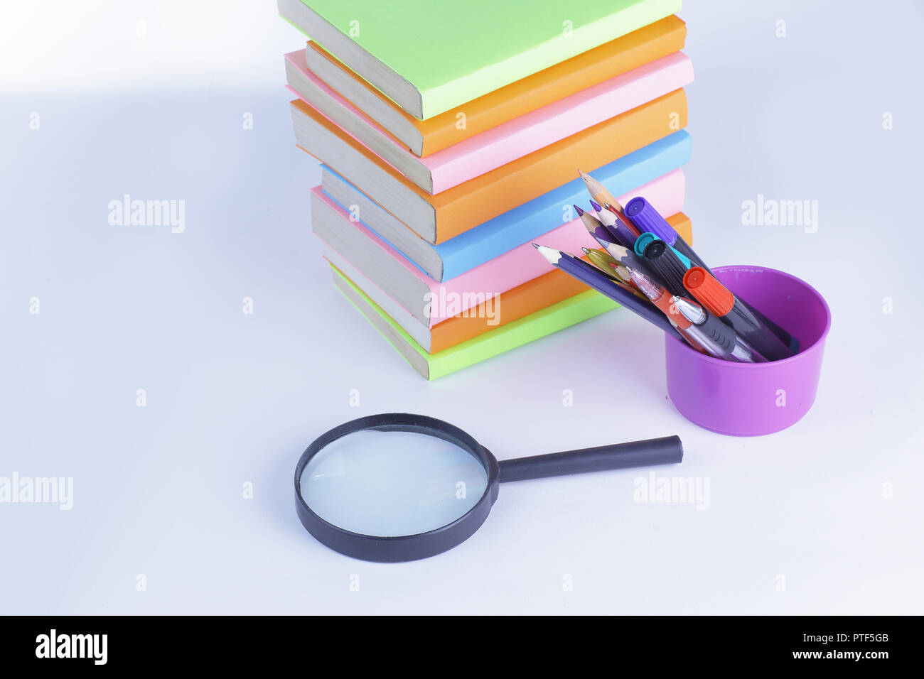 magnifying glass, pencils and stack of books on white background Stock ...