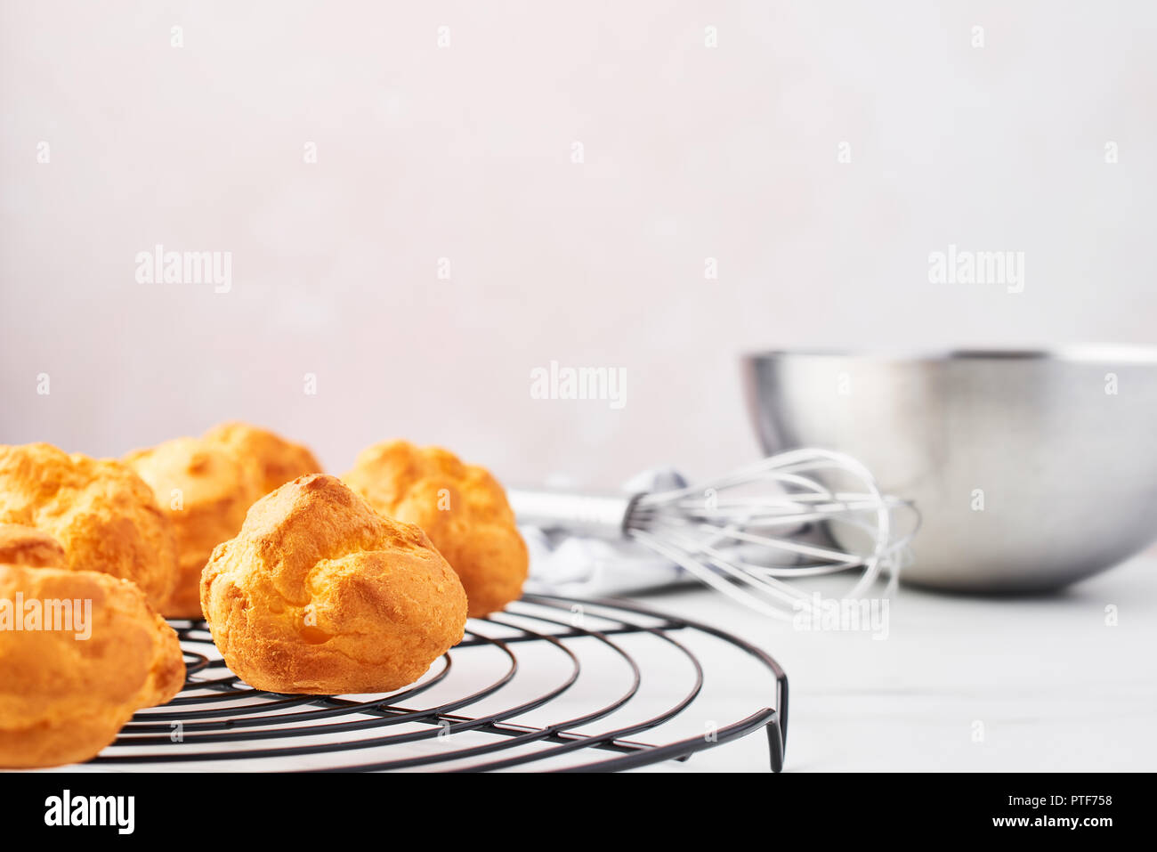 Baking concept. Bunch of fresh cream puff cakes on French wire rack ...